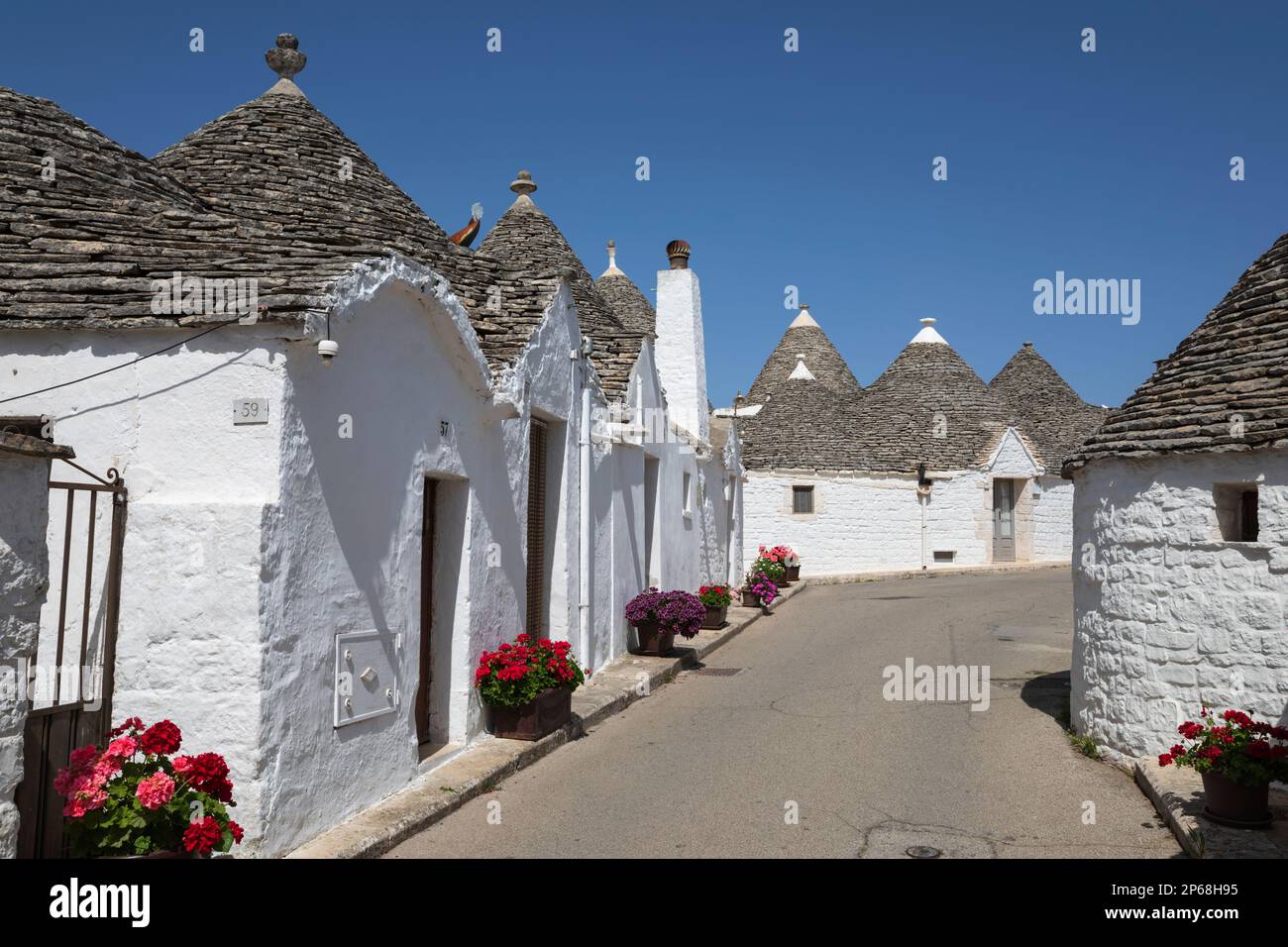 Whitewashed trulli houses along street in the old town, Alberobello ...