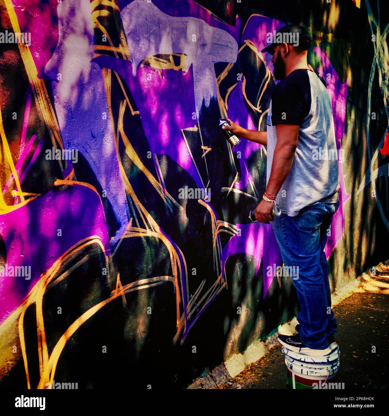 A Mexican street artist paints graffiti on the wall of a cemetery ...