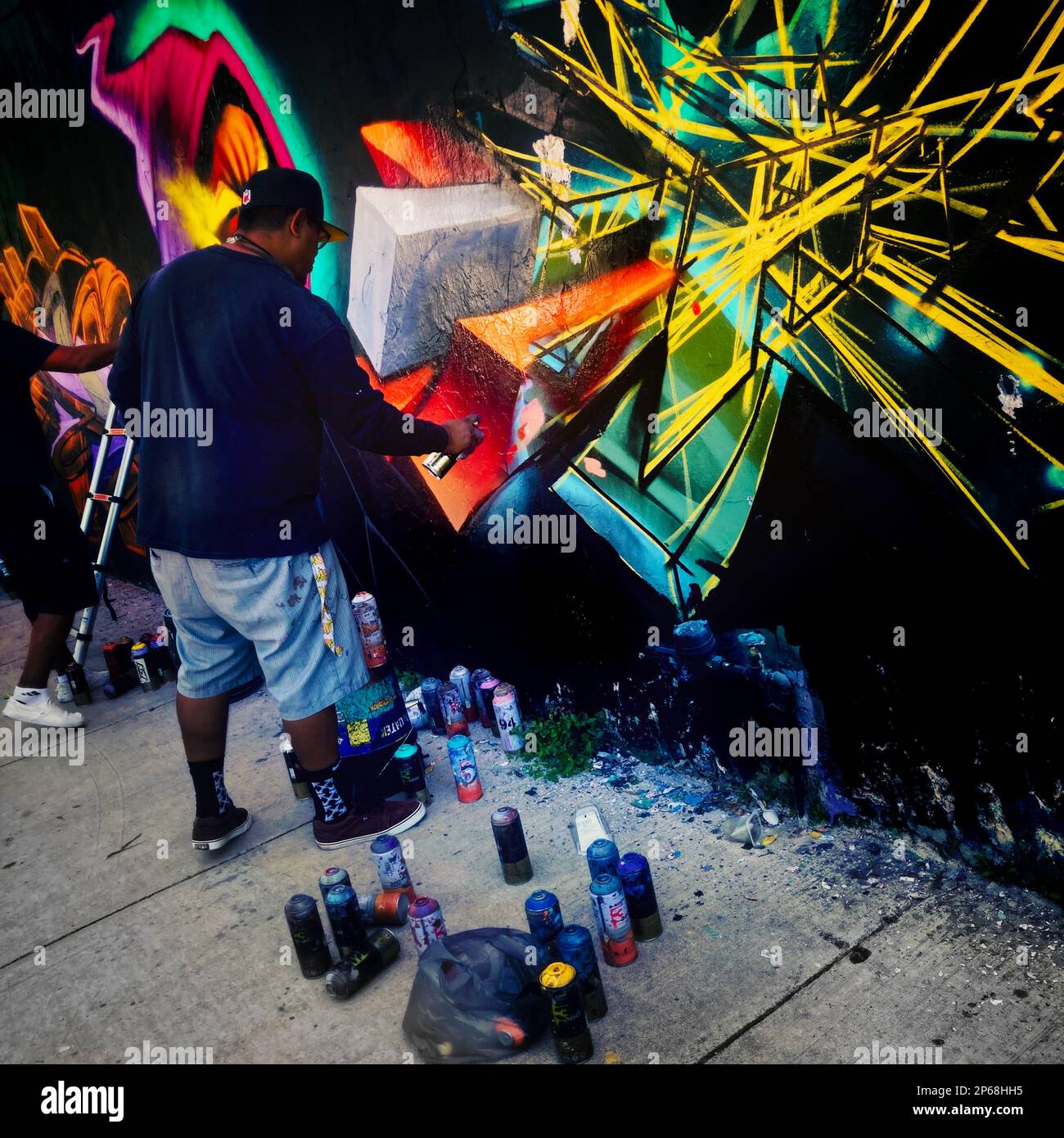 Mexican street artists paint graffiti on the wall of a cemetery during ...
