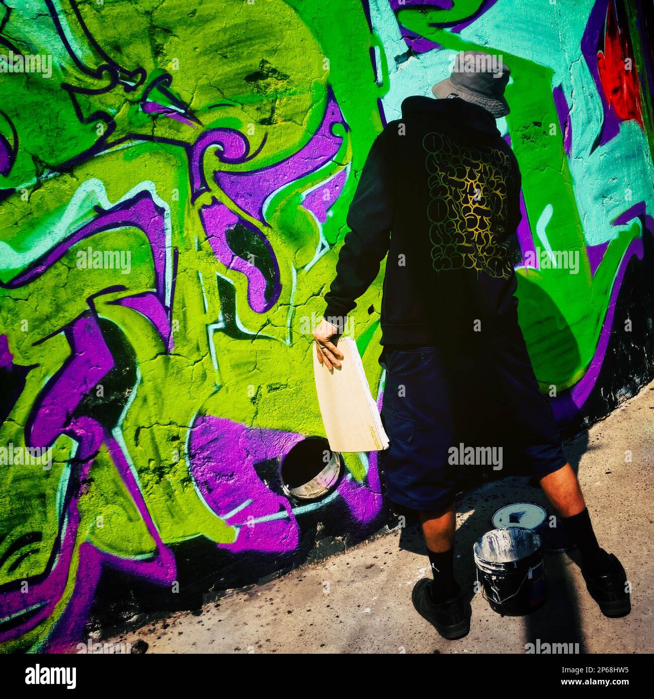 A Mexican street artist paints graffiti on the wall of a cemetery ...