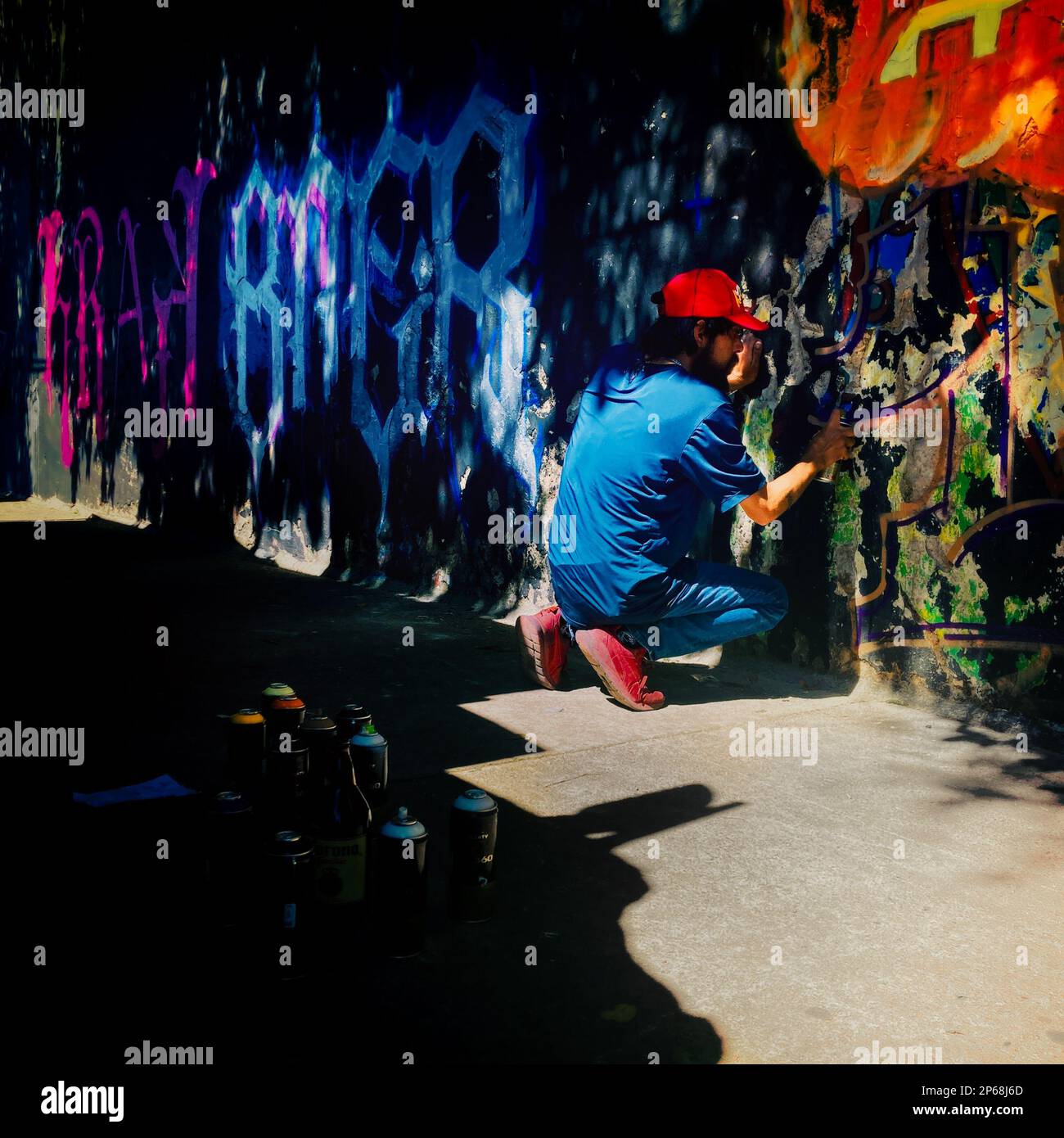 A Mexican street artist paints graffiti on the wall of a cemetery ...
