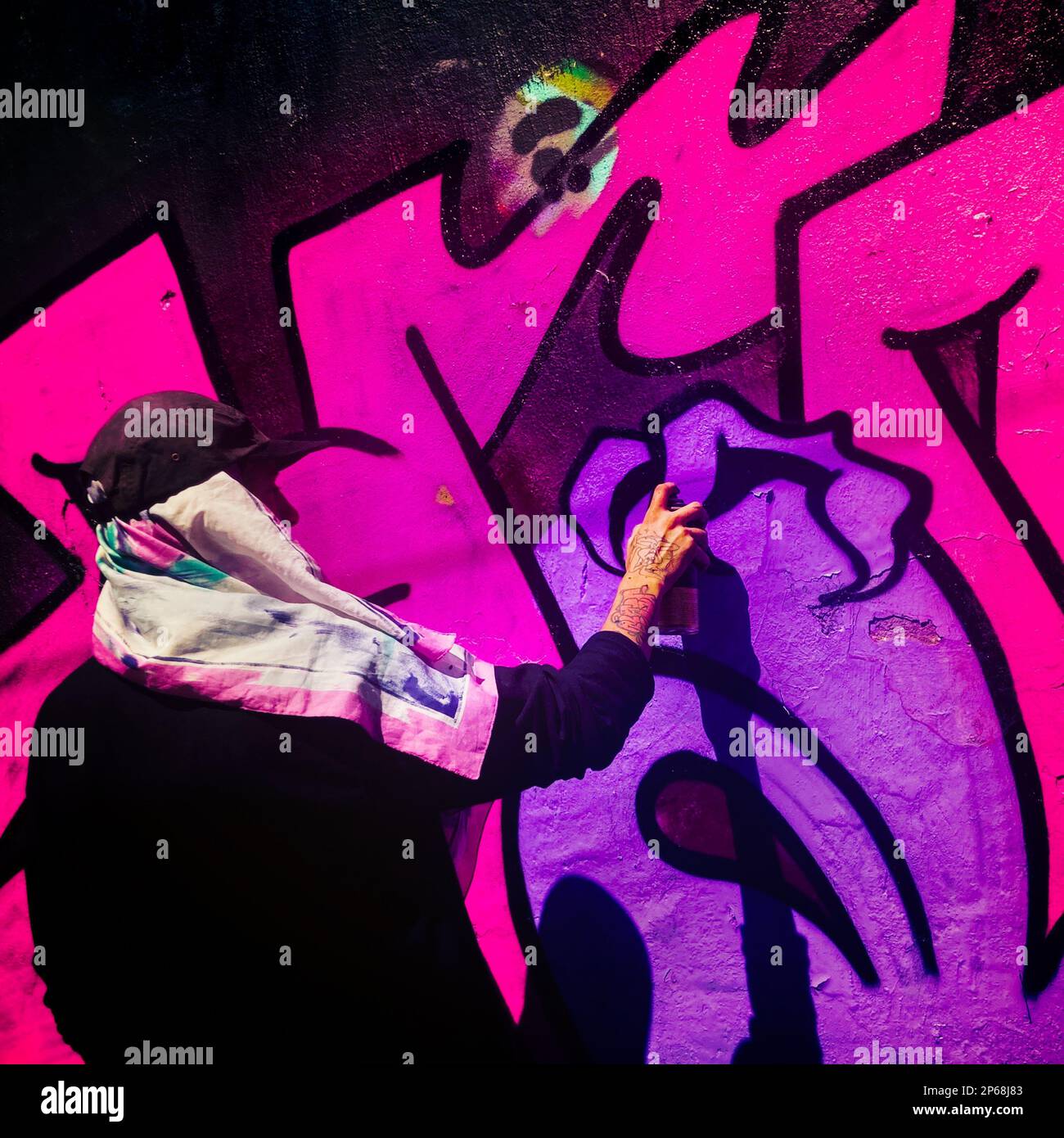 A Mexican street artist paints graffiti on the wall of a cemetery ...