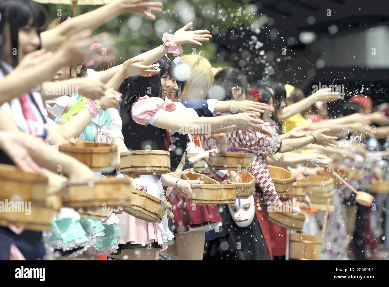 Girls dressed in maid costume splash water to cool down heat in front ...
