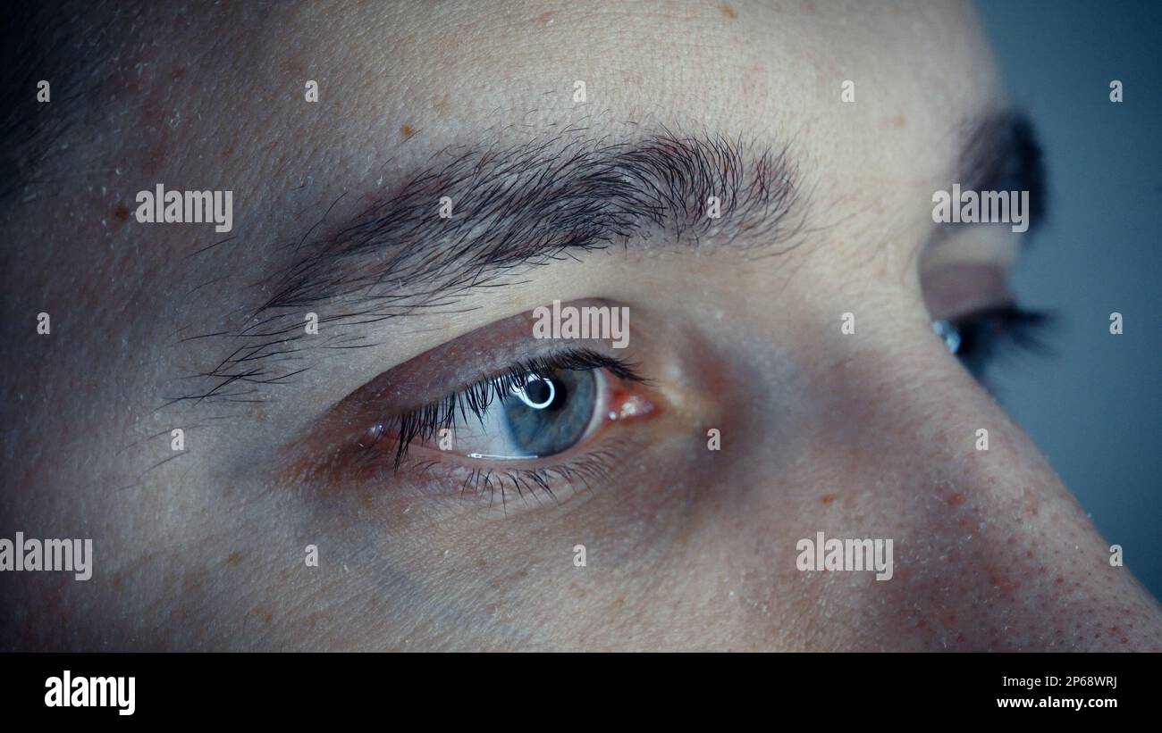 Close-up of blinking green eyes. A young man opens and closes his ...