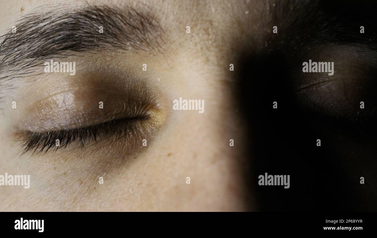 Close-up of blinking green eyes. A young man opens and closes his ...