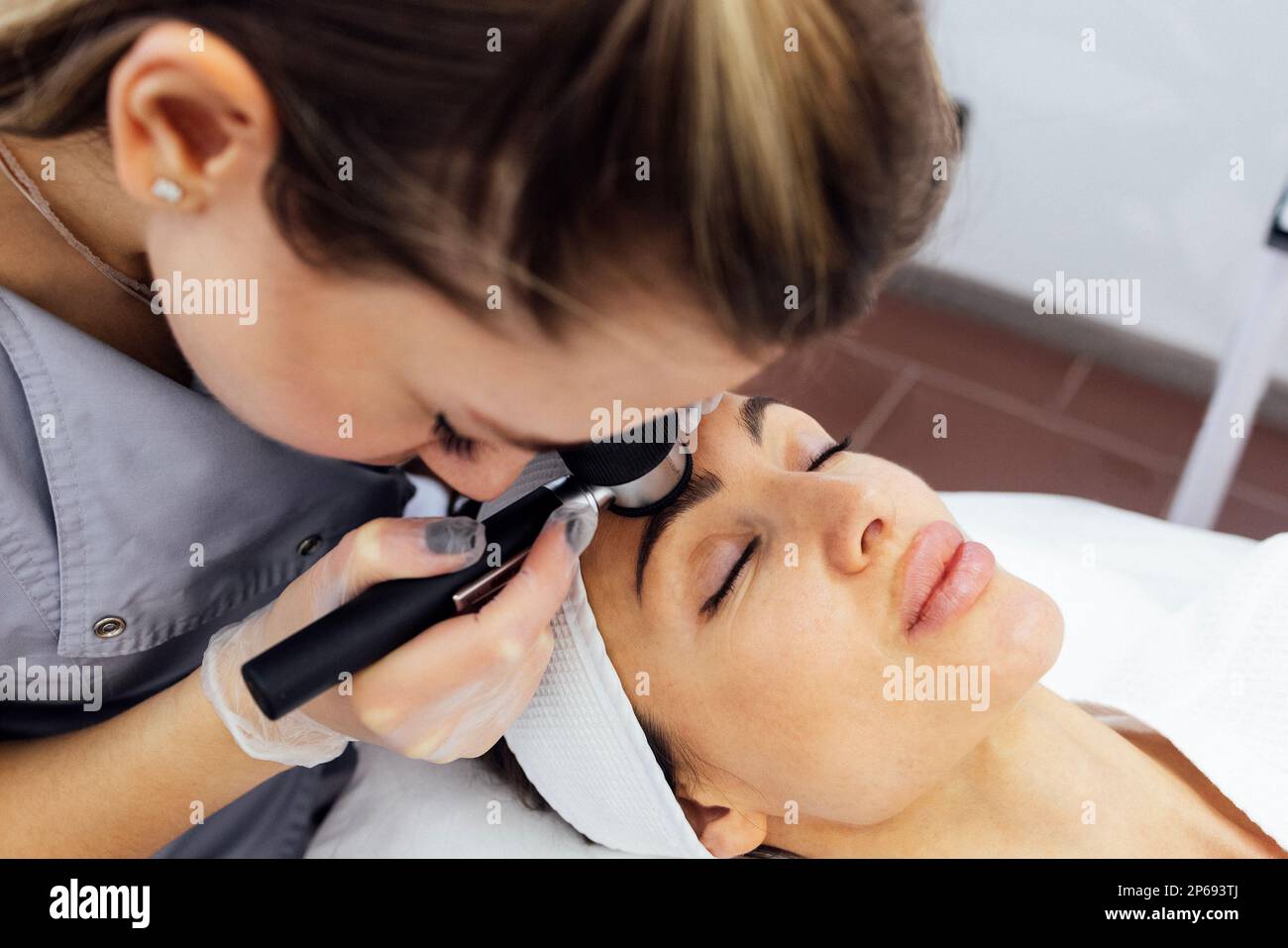 Doctor dermatologist examines skin of client face of beauty salon with ...
