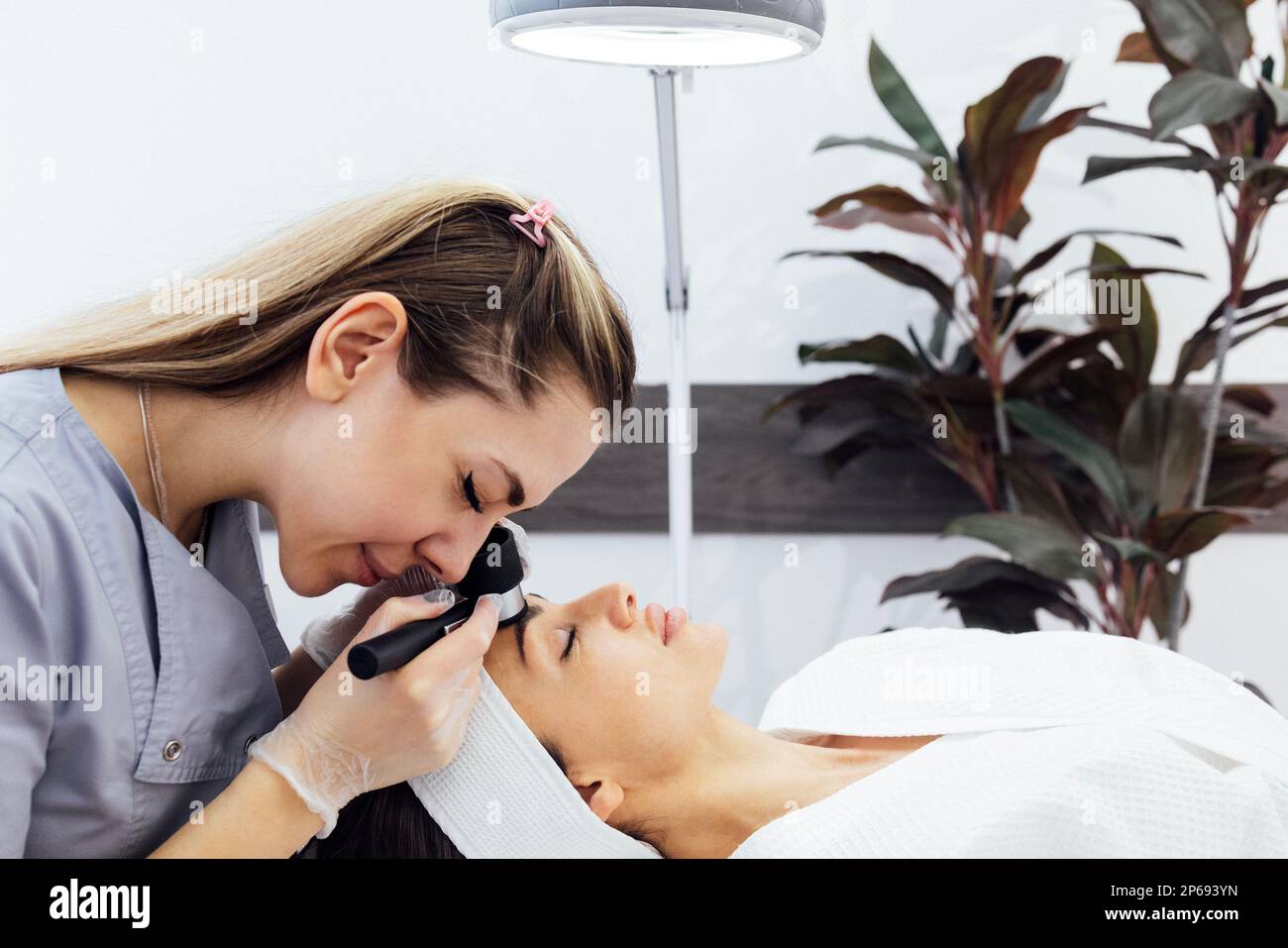 Doctor dermatologist examines skin of client face of beauty salon with ...