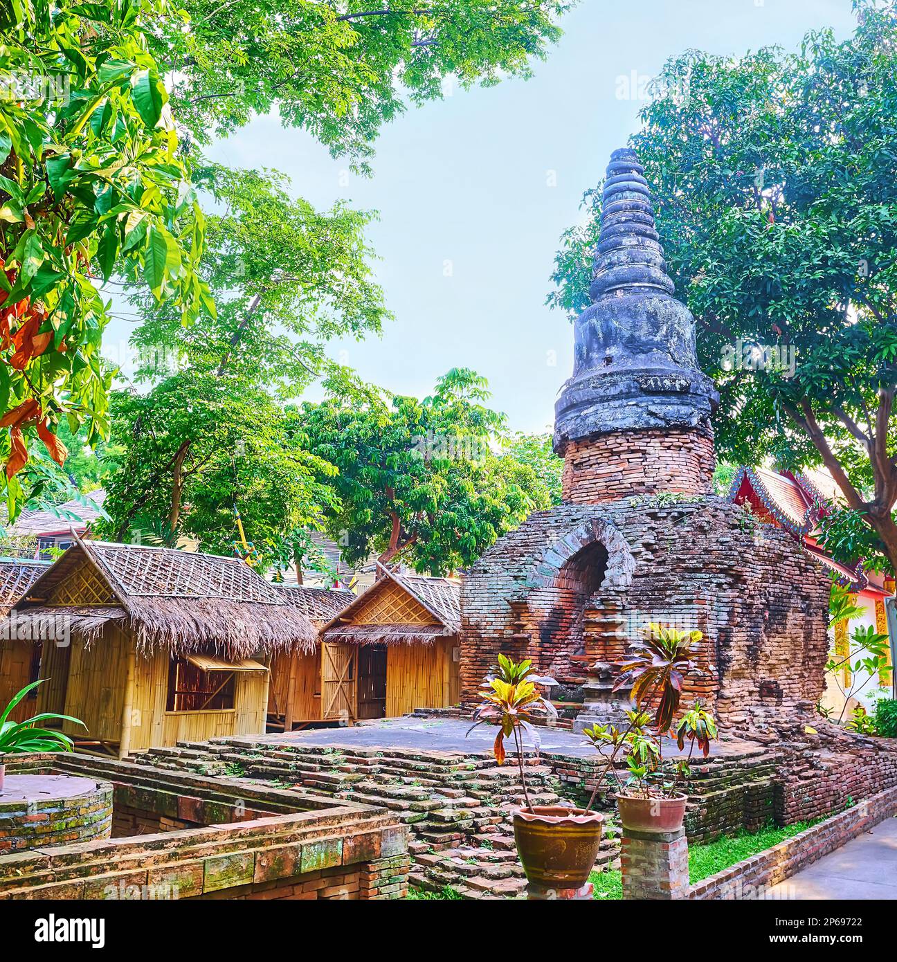 The brick ruins of the ancient Chedi, surrounded with lush trees and ...