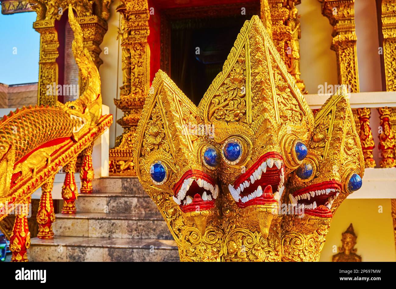 The golden three-headed roaring Naga serpent statue with big blue eyes ...