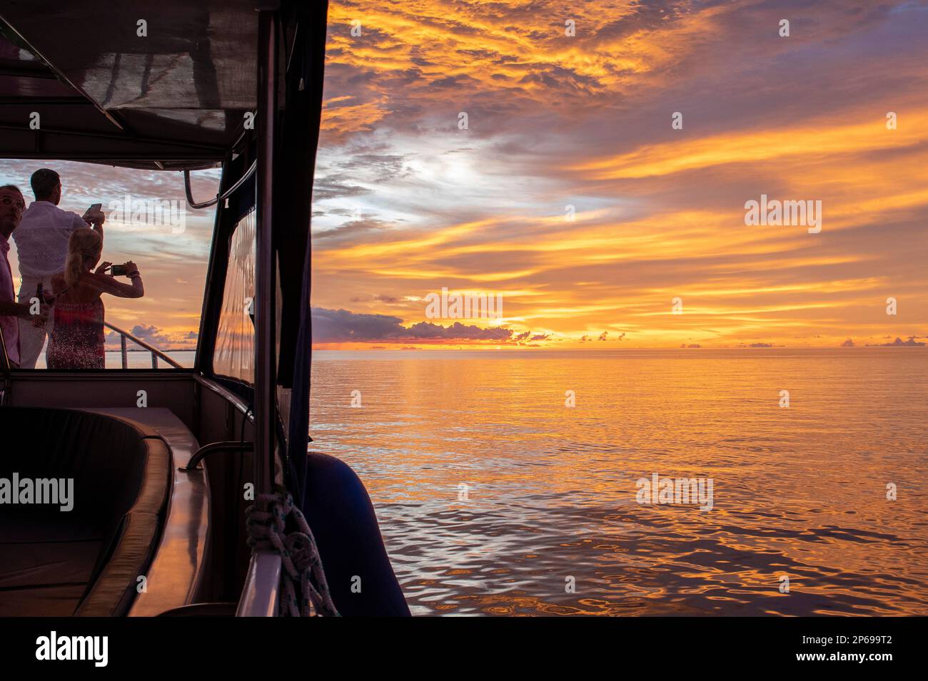 Tourists taking photos of a beautiful sunset during a sunset cruise ...