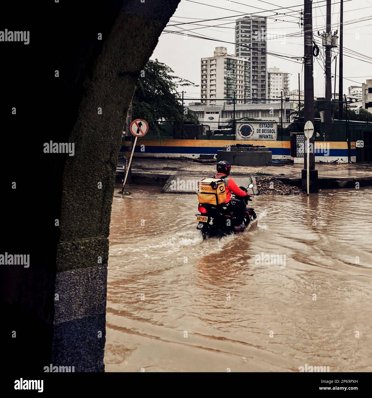 A Colombian motorcycle food delivery rider crosses a street flash ...