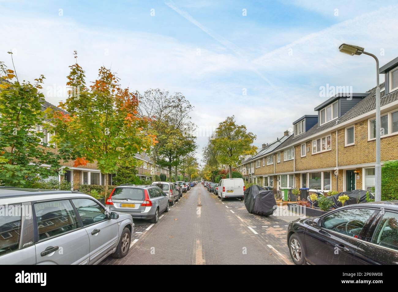 a street with cars parked on the side and houses in the back ground ...