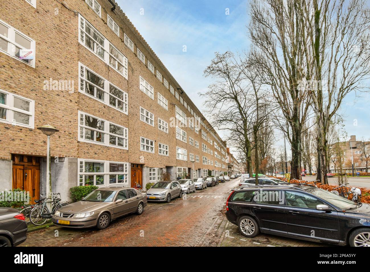 some cars parked on the side of a street in front of a brick building ...