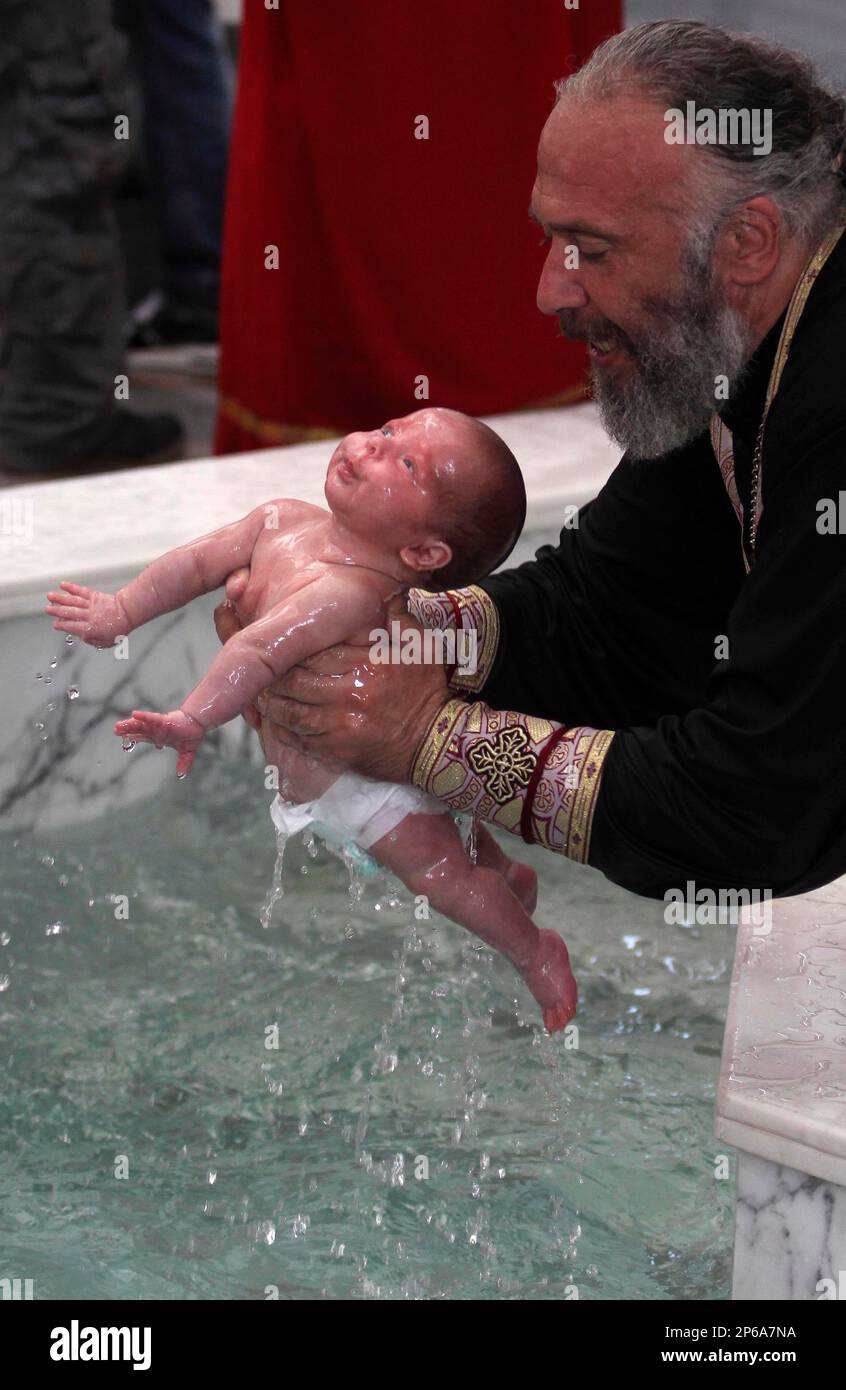 A Georgian Orthodox priest baptizes a baby during a mass baptism ...
