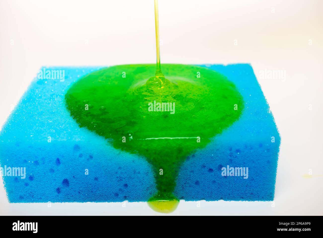 green liquid soap dripping on a blue sponge on a white background Stock ...