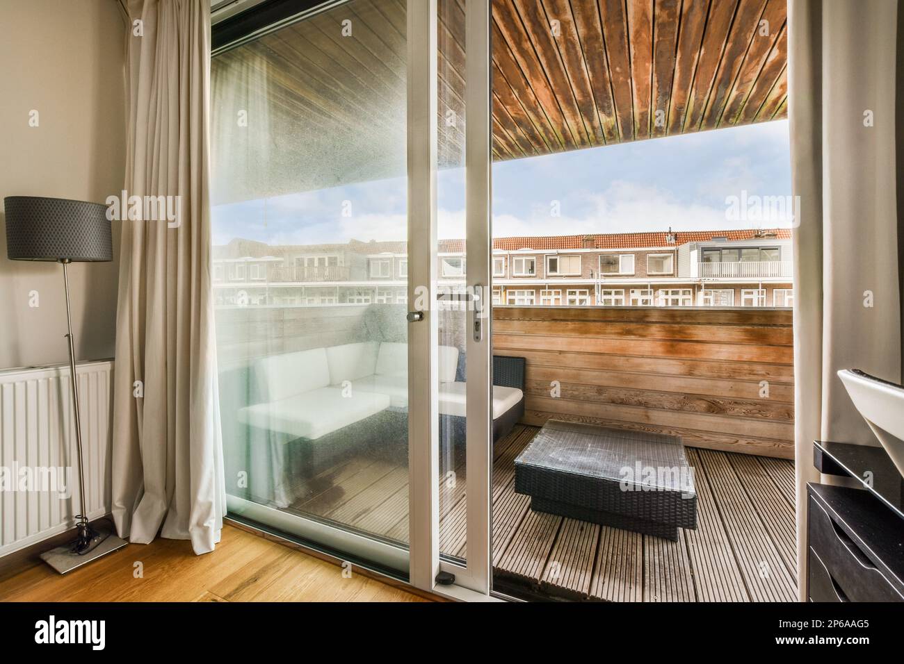 a living room with wood floors and sliding glass doors that open to the ...