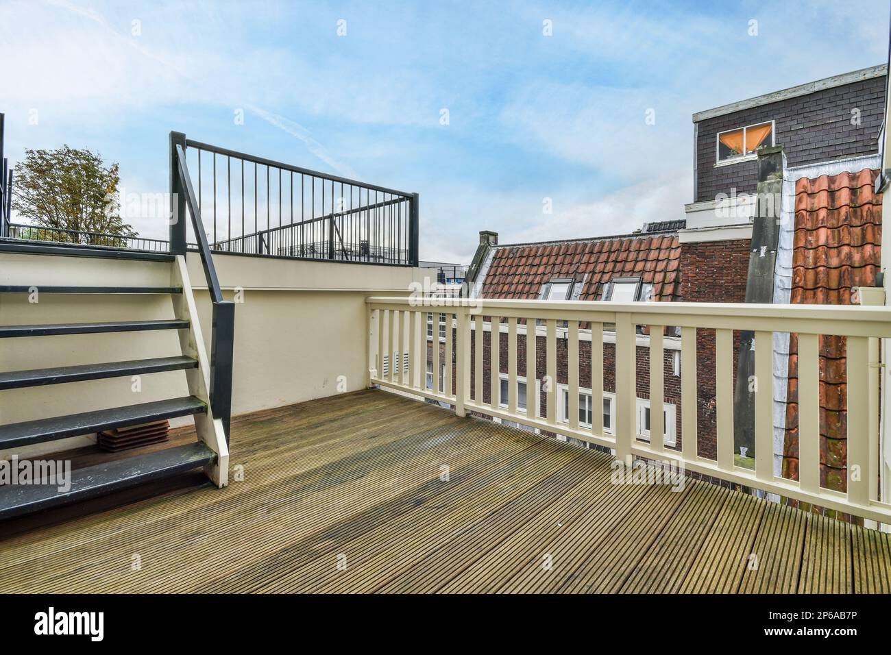 a wooden deck with white railings and red tile roofing on a house in ...