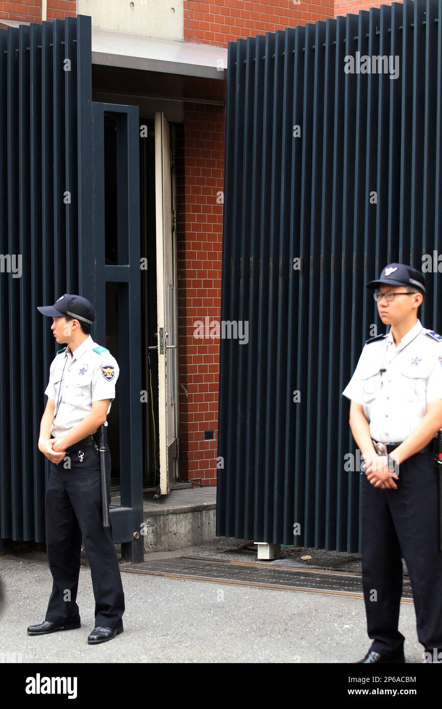 Police officers stand guard outside the damaged main gate of the ...