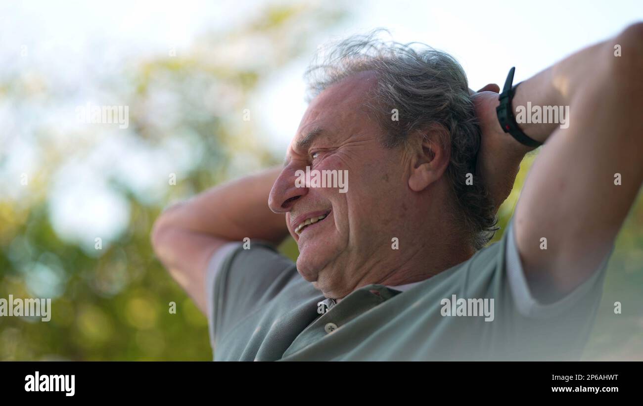 One relaxed happy retired senior man at outdoors park with hands behind ...