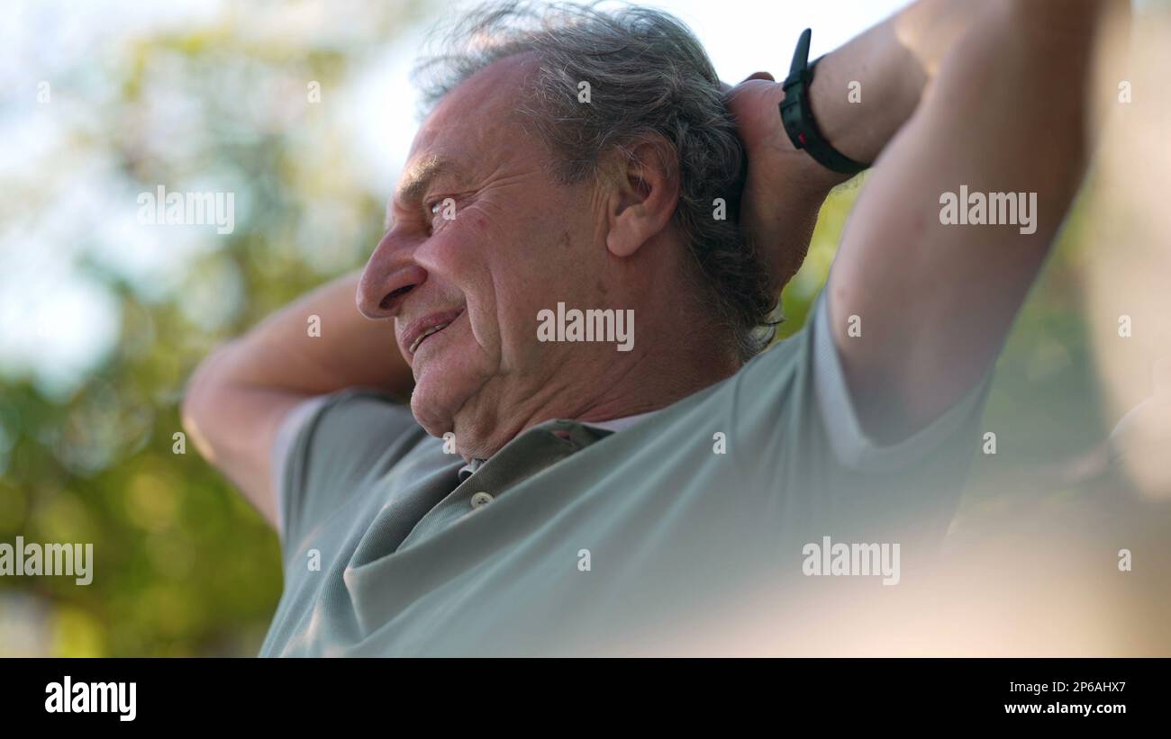 One relaxed happy retired senior man at outdoors park with hands behind ...