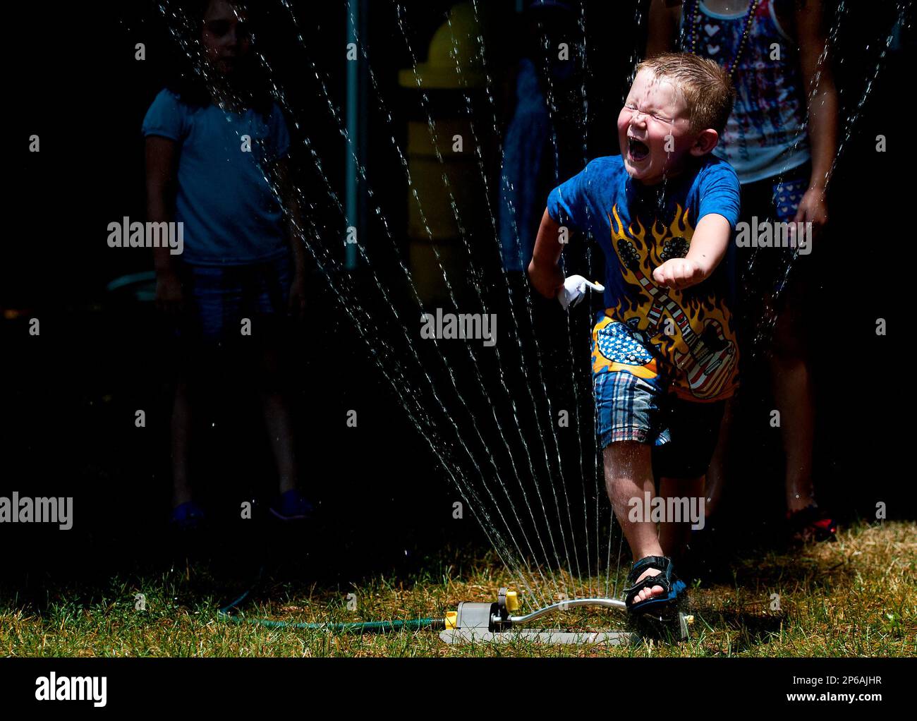 Lincoln McFate, 3, runs through a sprinkler during the Independence Day ...