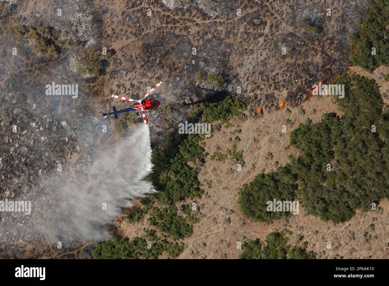 A helicopter tries to drown out the fire line on the mountain behind ...