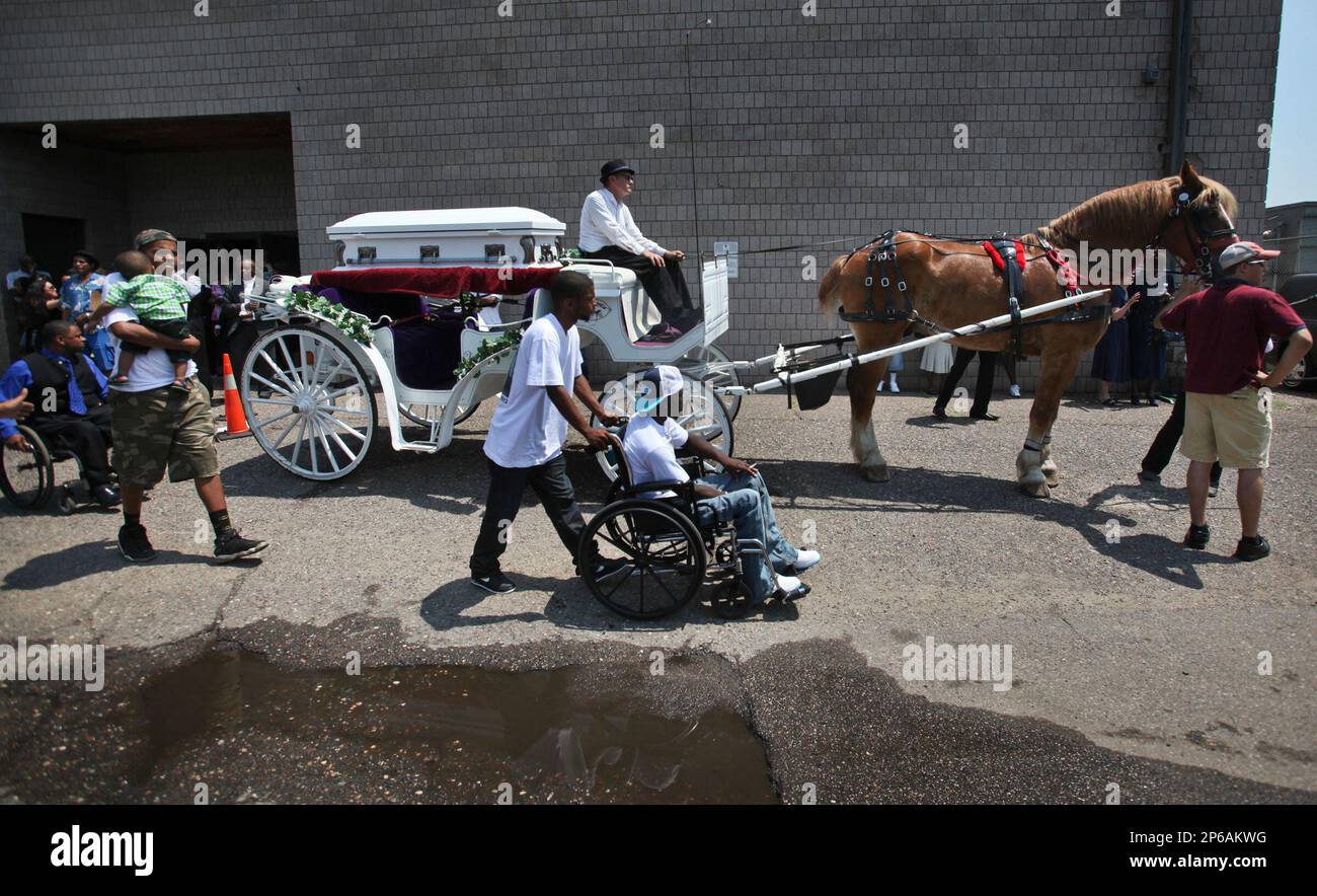 Mourners pass the horse-drawn hearse carrying the coffin of Nizzel ...