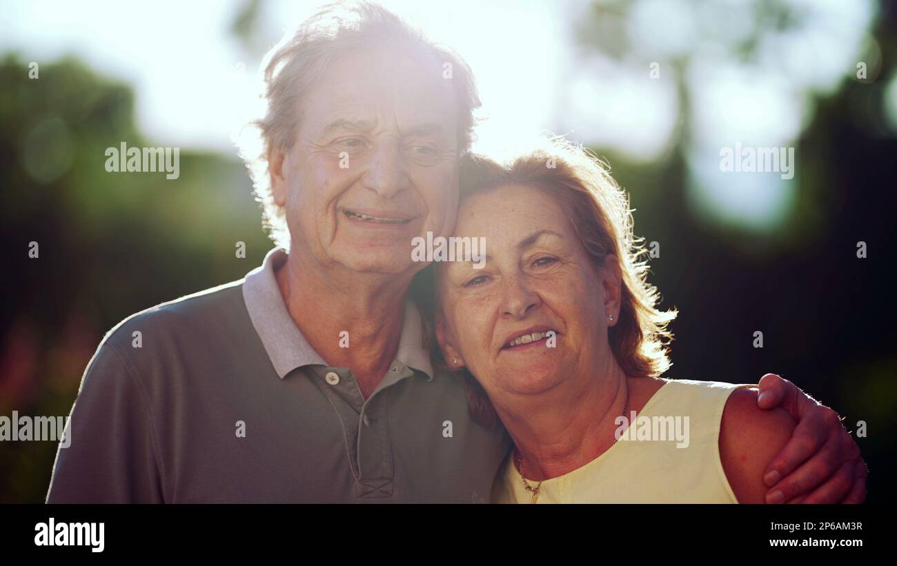 Senior couple smiling at camera in park. Portrait faces of husband with ...