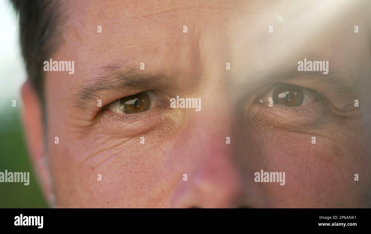 Macro eyes close up of a man with serious expression with sunlight ...