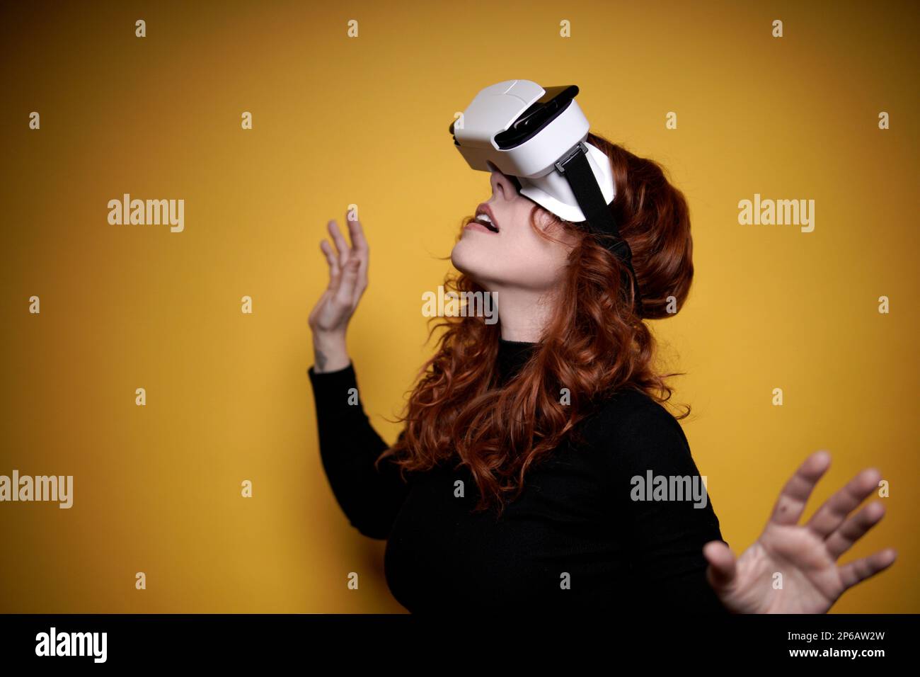 woman with virtual reality goggles on yellow background looking up in ...