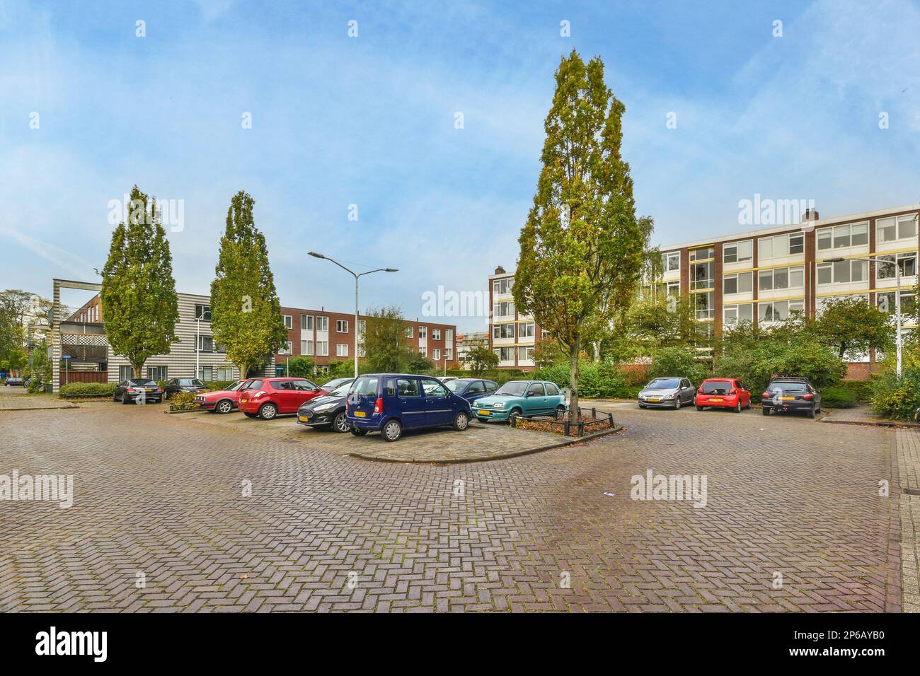 a parking area with cars parked on the side and trees lining the street ...
