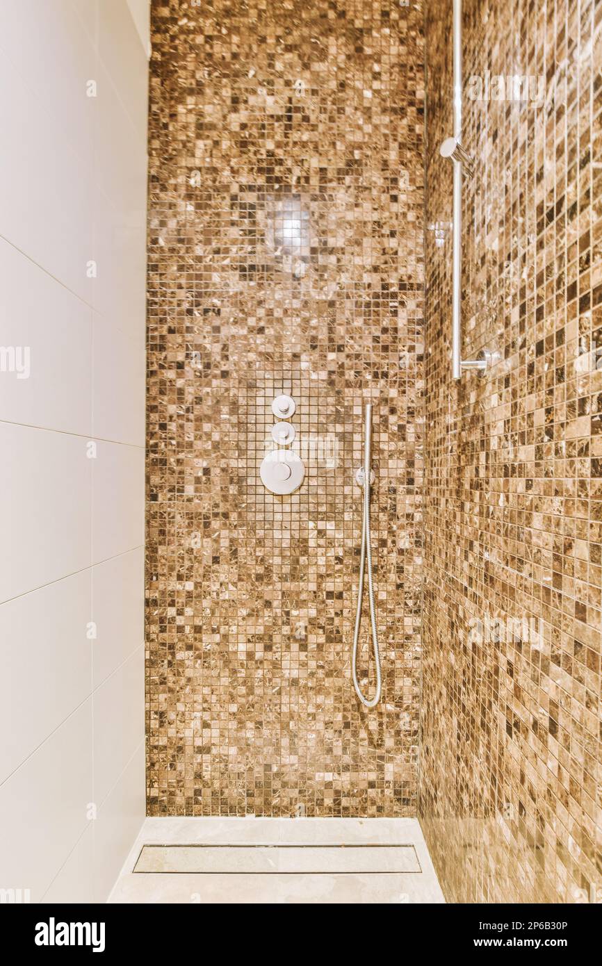 a walk in shower with brown and white tiles on the wall behind it is a ...