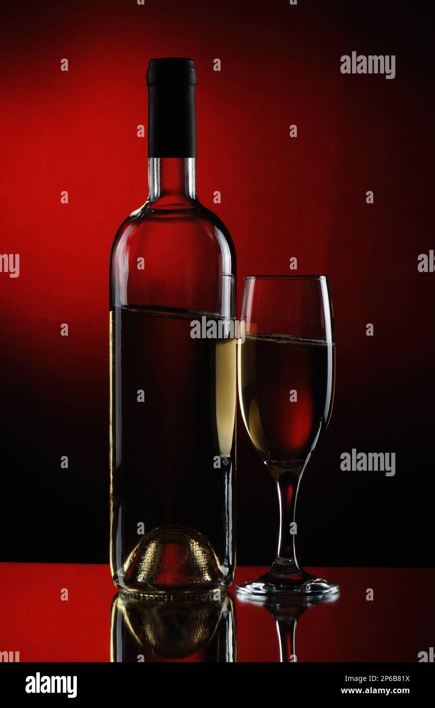 bottle and glass of red wine with reflection on a brown background ...