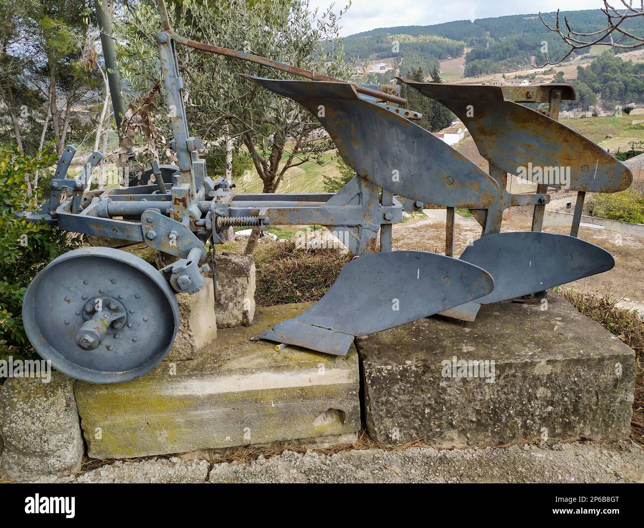 A steel plow is situated in the front yard of a rural home surrounded ...