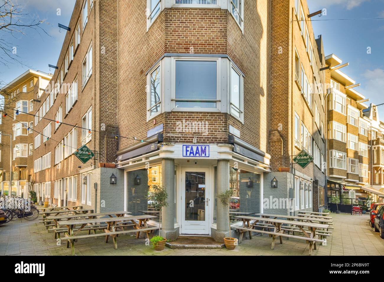 a brick building with tables and benches on the sidewalk in front of it ...