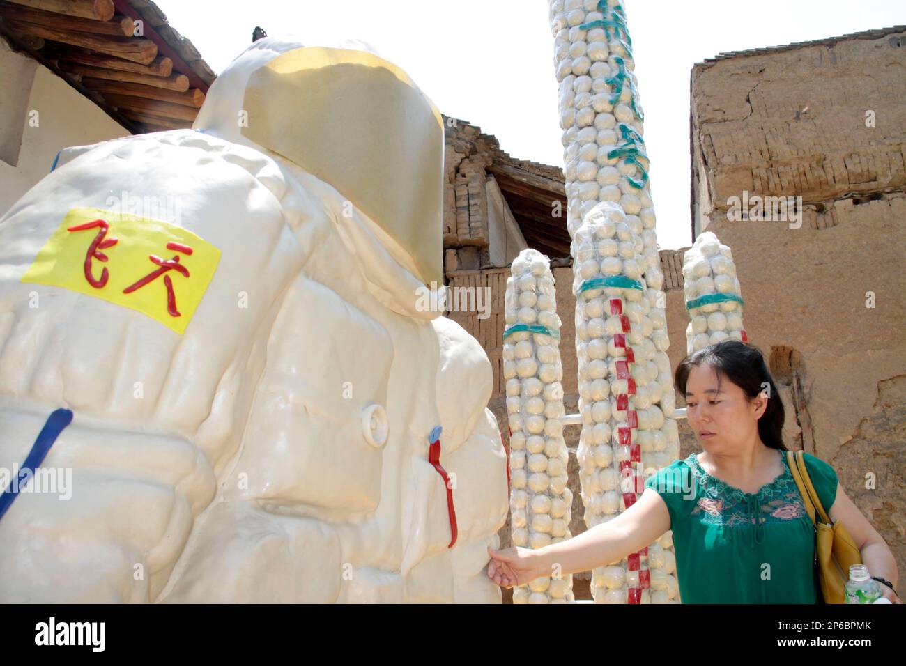 A woman walks past the dough sculpture of an astronaut and Shenzhou 9 ...