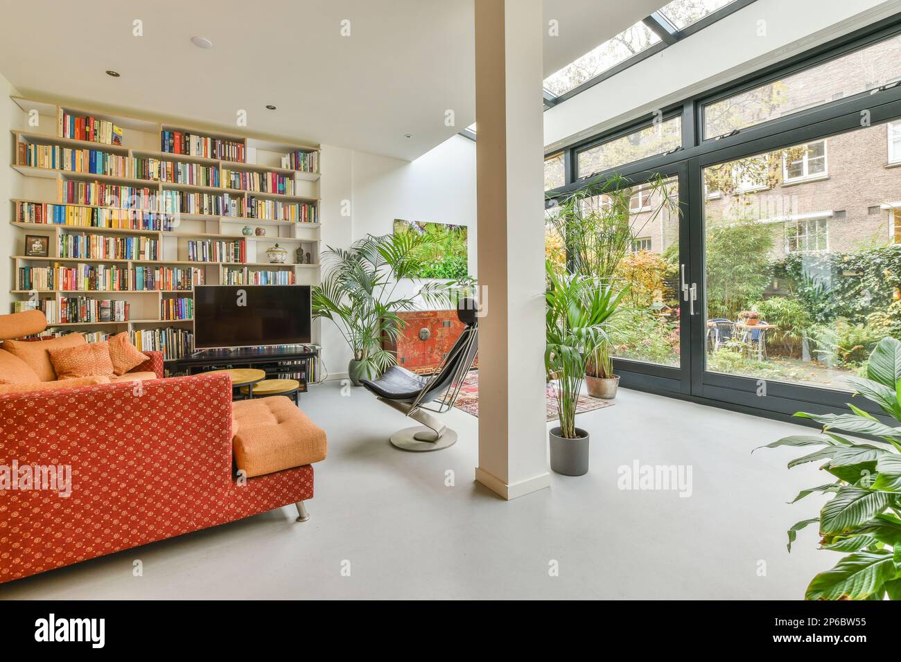 a living room with lots of books on the shelves and an orange couch in ...