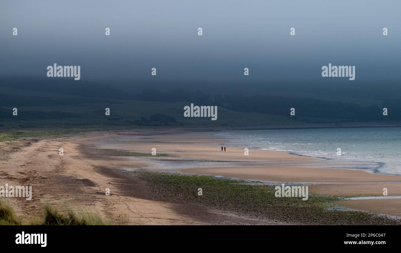 Couple walking on Brora beach Stock Photo - Alamy