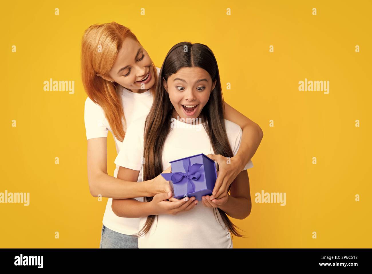 Young teen girl giving gift box to her mother on color background. Happy family. Mother and ...