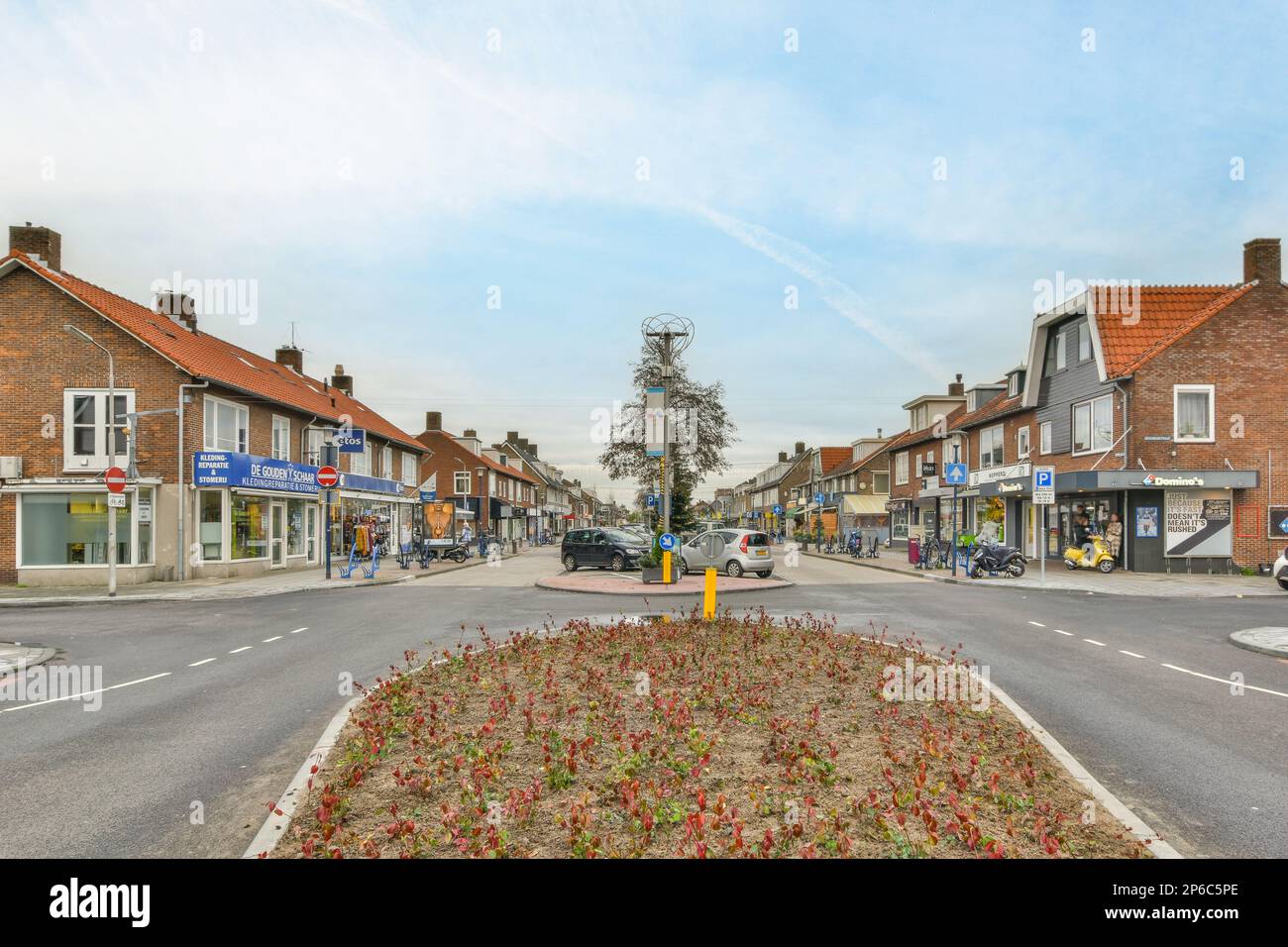 a city street with buildings and flowers in the middle of the road ...
