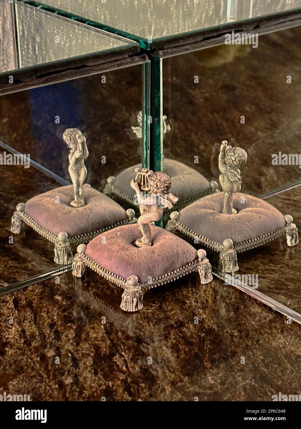 Cherubs playing harps on pedestal or cushions show a triple mirror ...