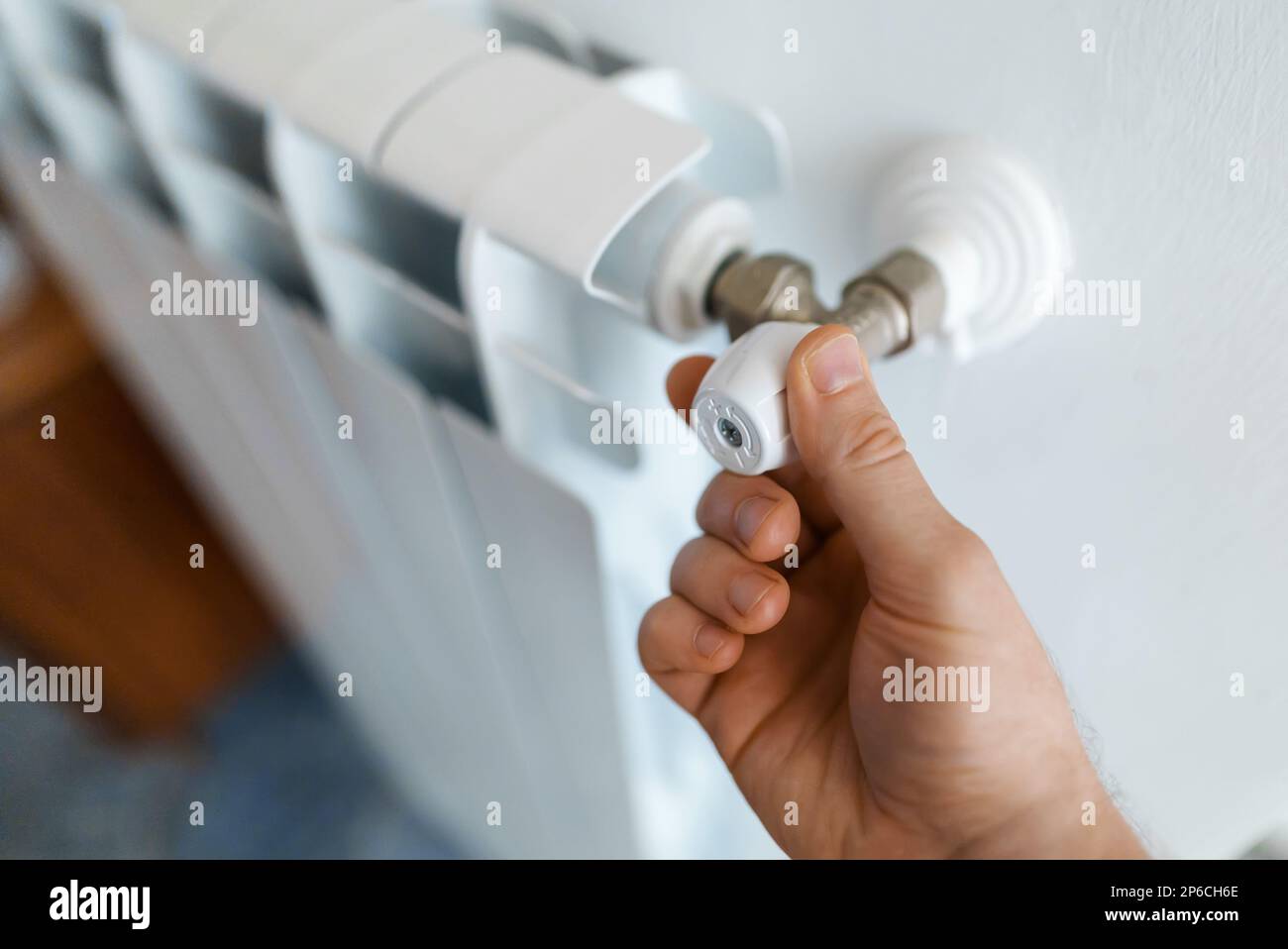 Male hand adjusting thermostat to turn on the radiator heater at home ...