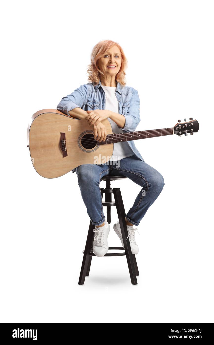 Female Mature Artist With An Acoustic Guitar Sitting On A Chair Female Mature Artist With An Acoustic Guitar Sitting On A Chair