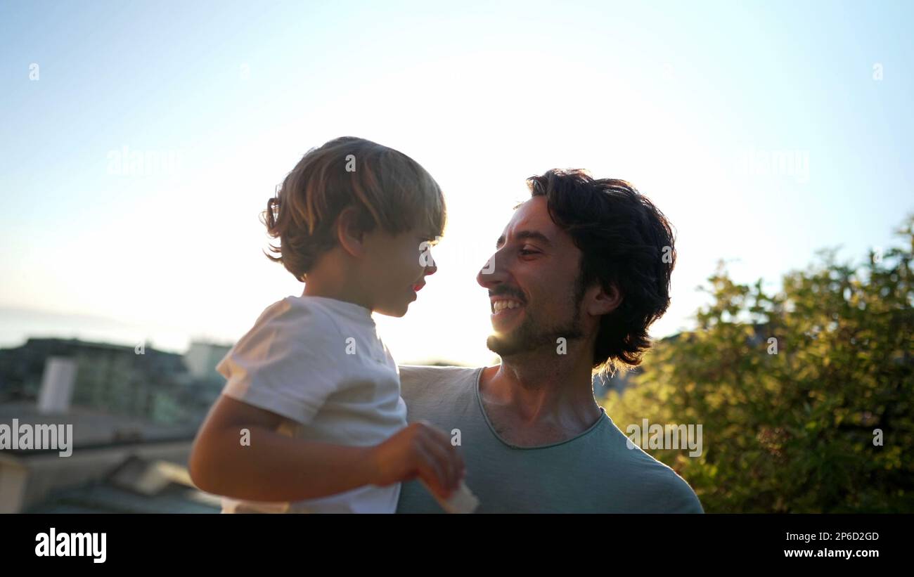 Child embracing father in sunset time. Father and son bonding moment ...