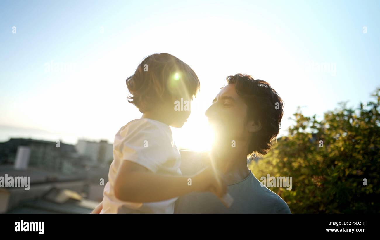 Child embracing father in sunset time. Father and son bonding moment ...