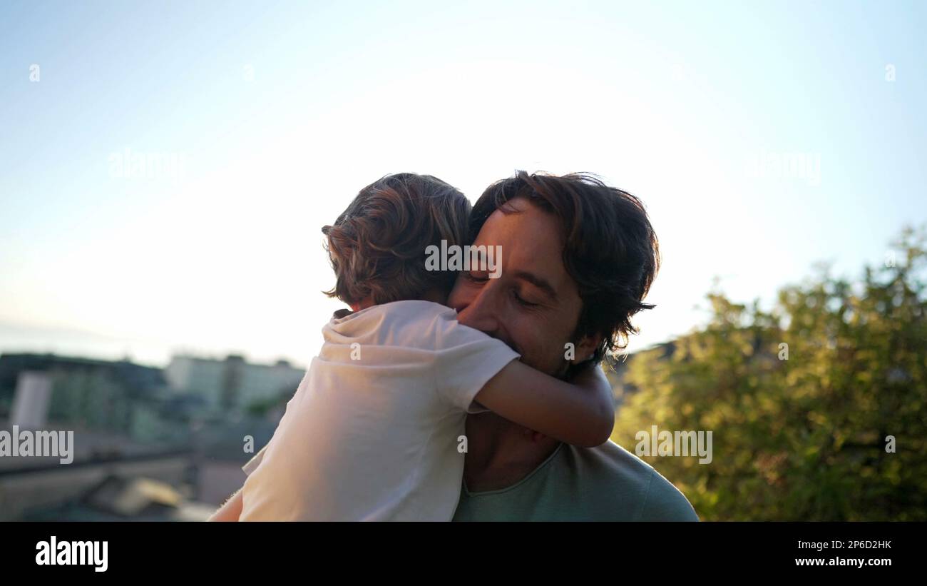 Child embracing father in sunset time. Father and son bonding moment ...