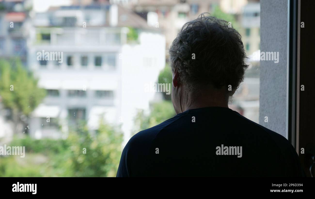 Back of a contemplative senior man looking out window. Pensive older ...
