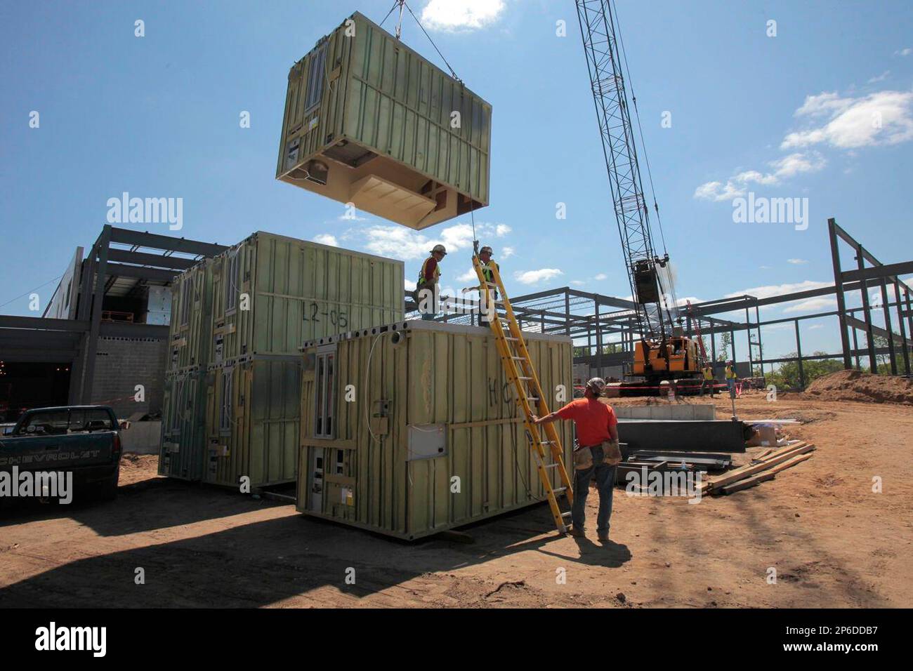 Construction workers use a crane to install a prefabricated two-person ...