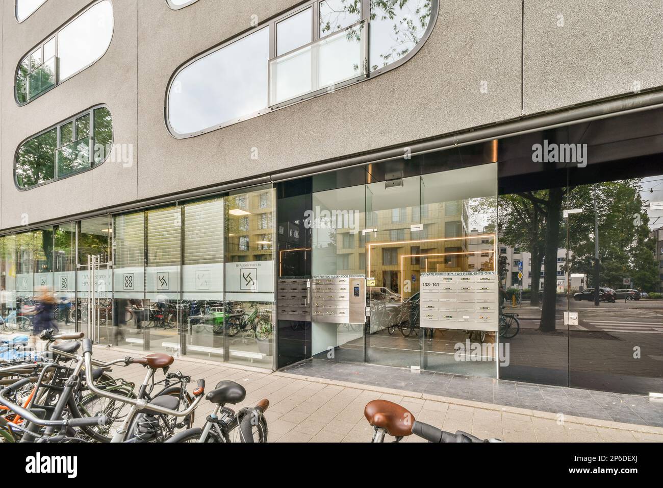 some bikes parked in front of a large glass building with windows on ...