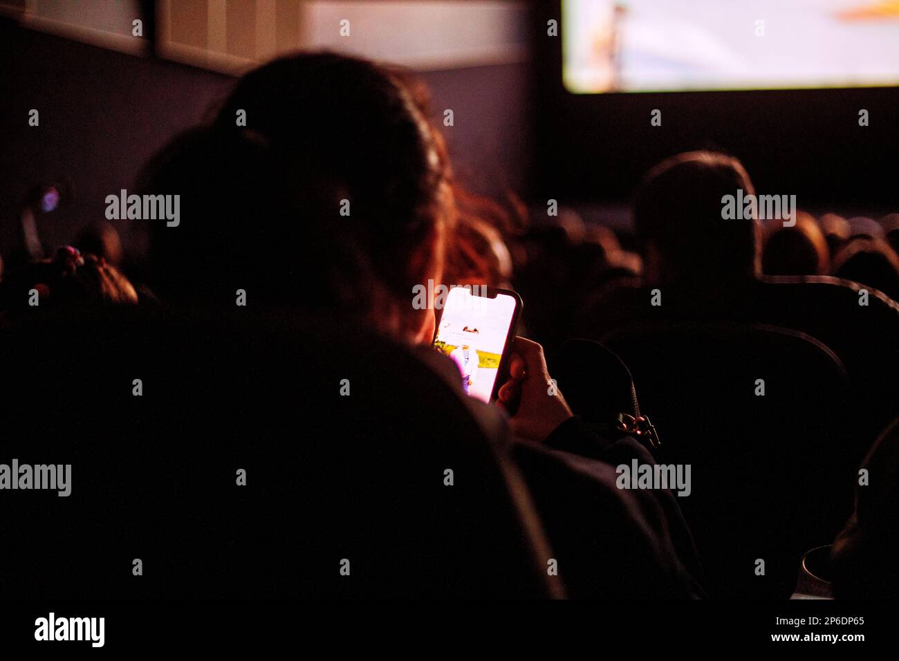 Girl looks into the phone in the cinema before watching a movie ...